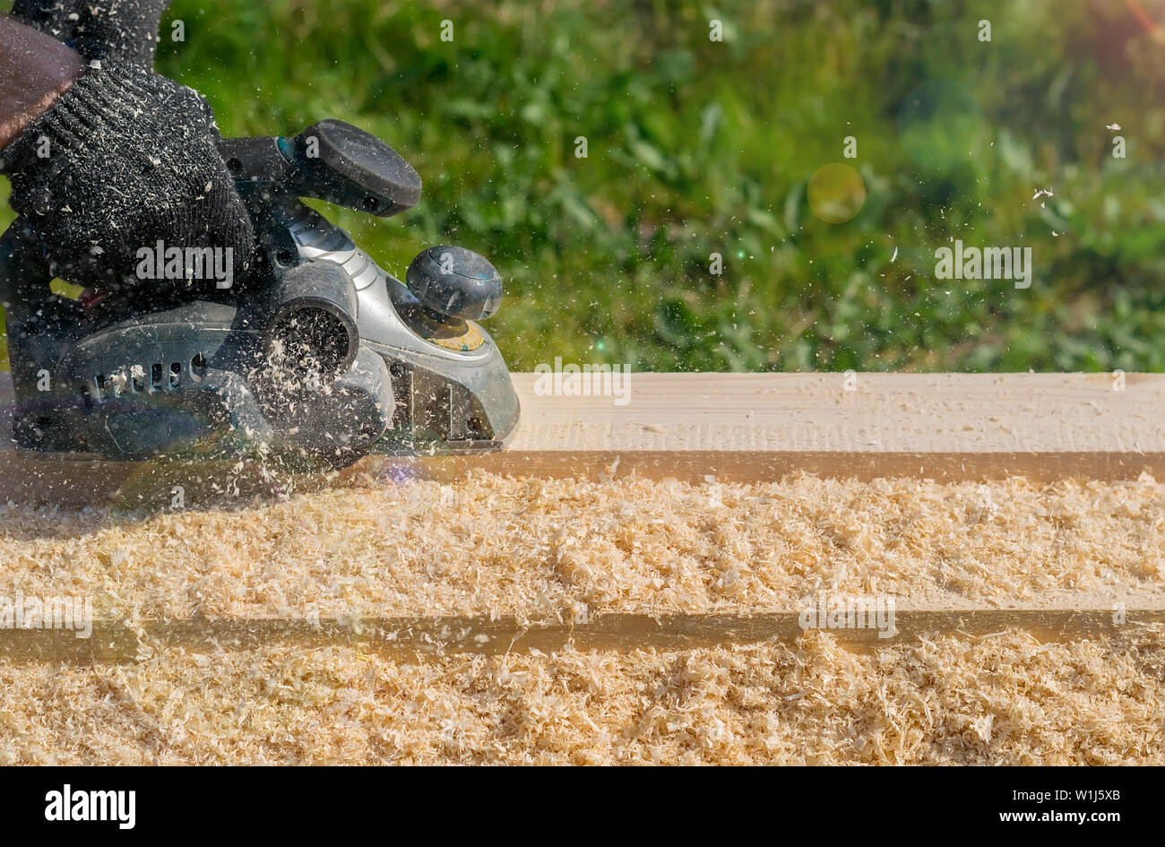 man planing boards with electric tools, chips flying in all directions ...