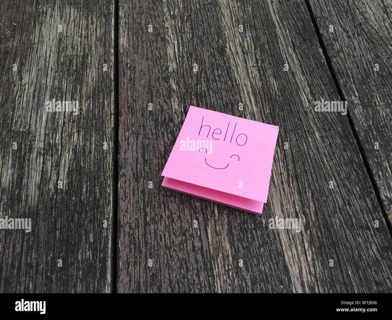 Hello text letter on wooden background. Top view pink reminder note ...