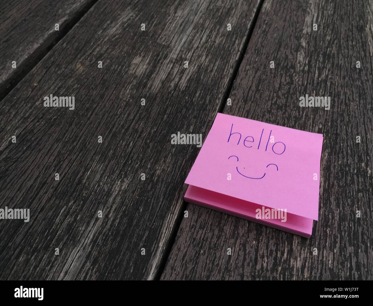 Hello text letter on wooden background. Top view pink reminder note ...