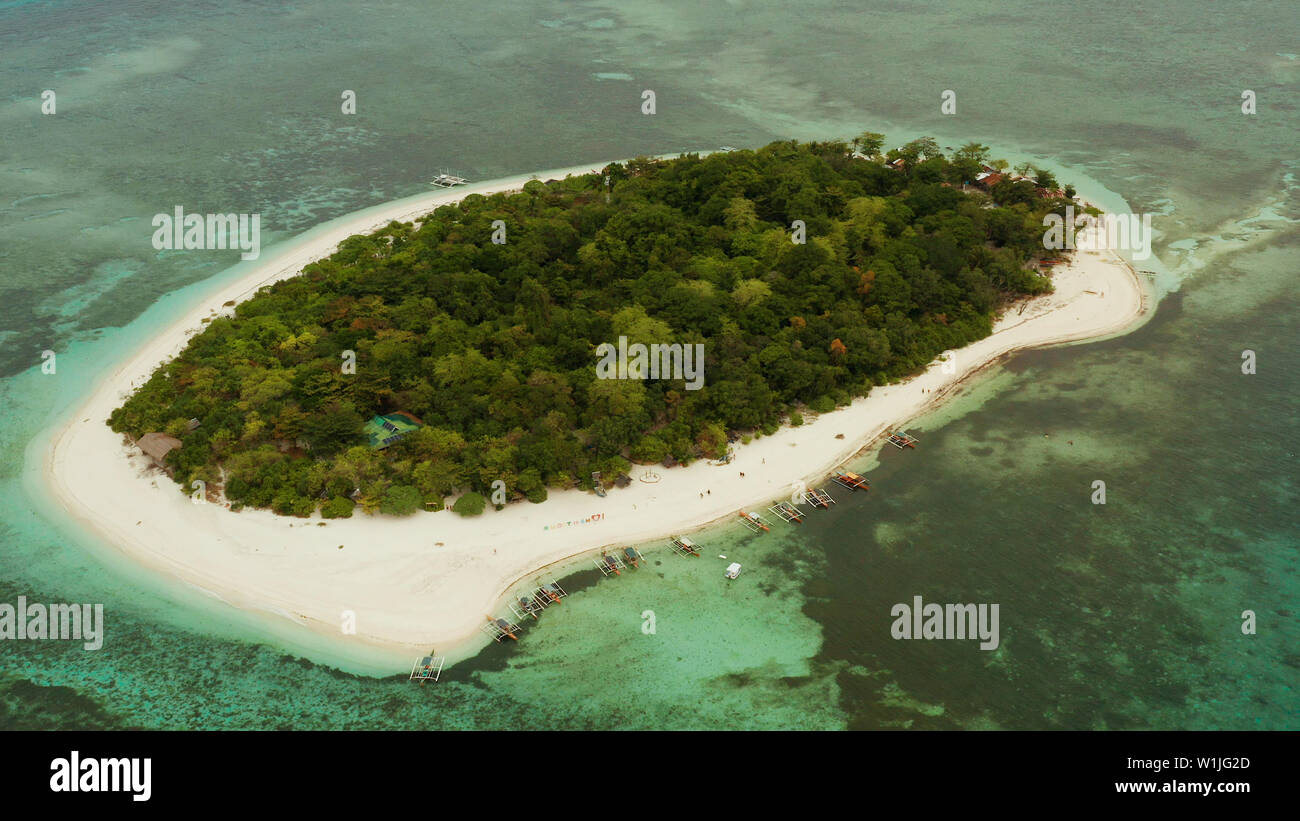 Tropical island and sandy beach surrounded by atoll and coral reef with ...