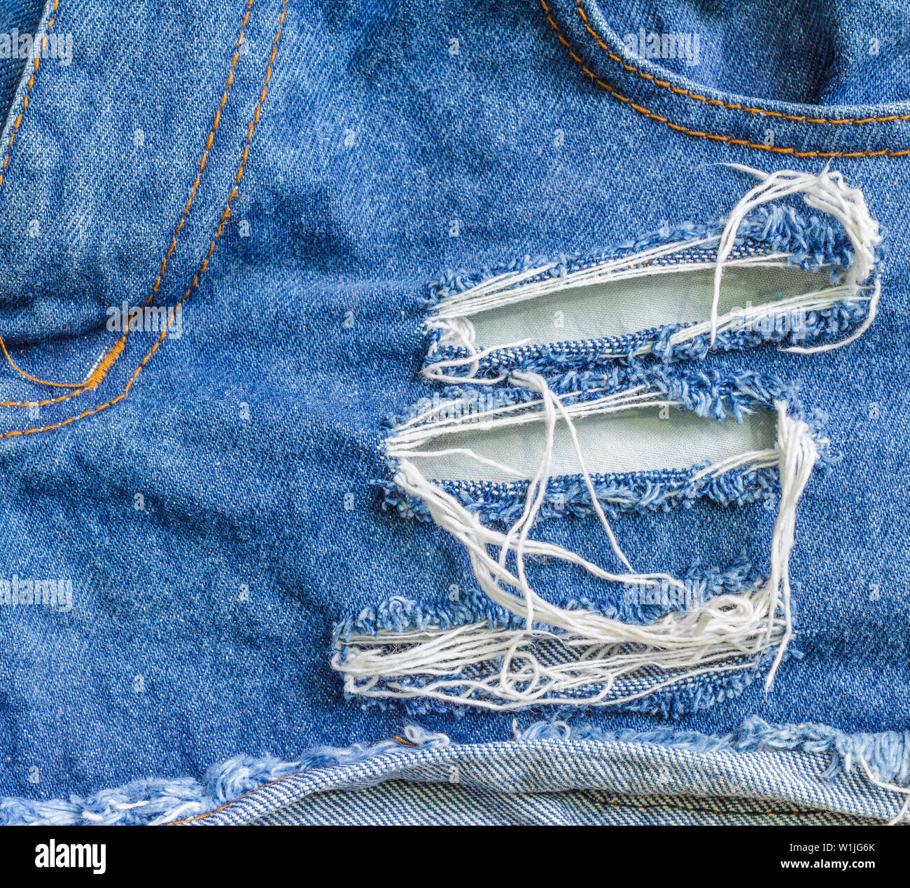 Detail of torn blue denim, front view Stock Photo - Alamy