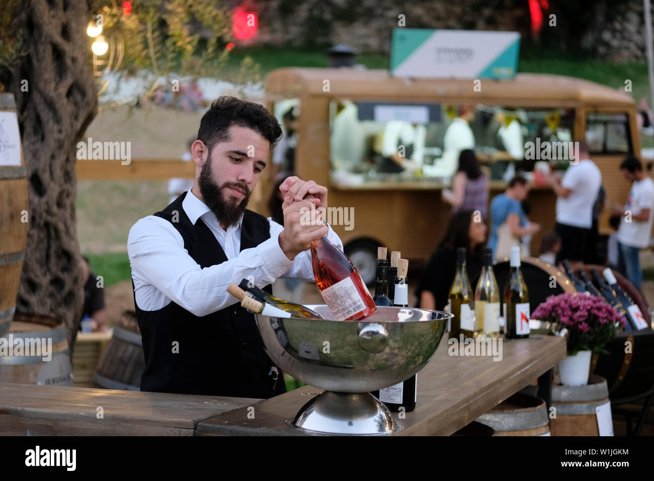 A bartender opening a bottle of wine at the Food Truck Festival taking ...