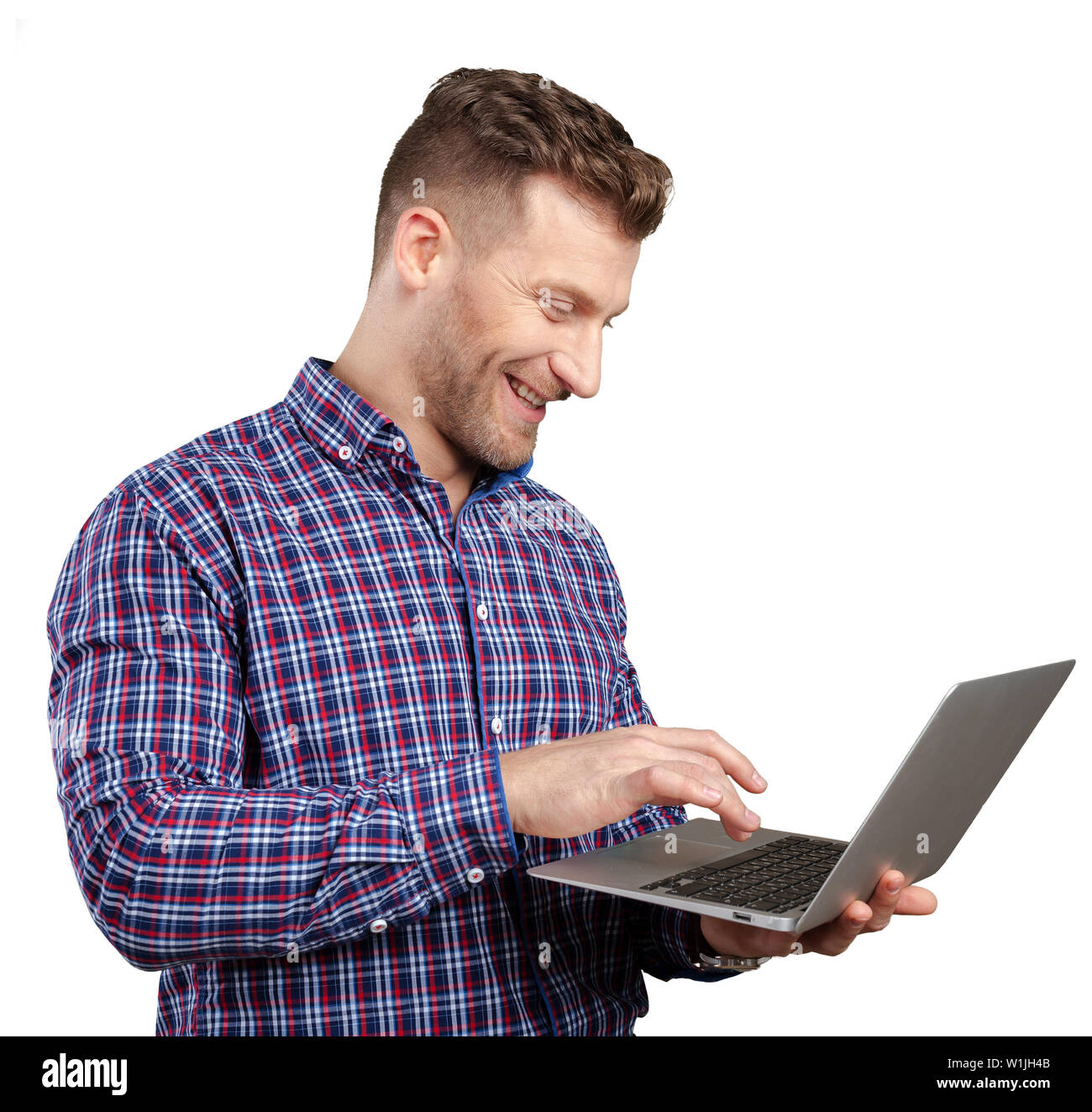 Young man standing, holding laptop computer, working Stock Photo - Alamy