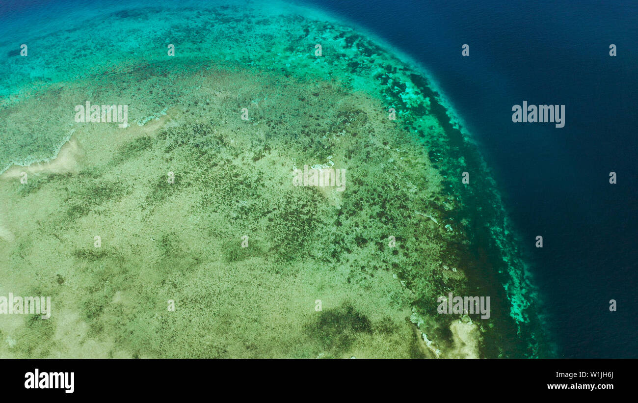Tropical island and sandy beach surrounded by atoll and coral reef with ...