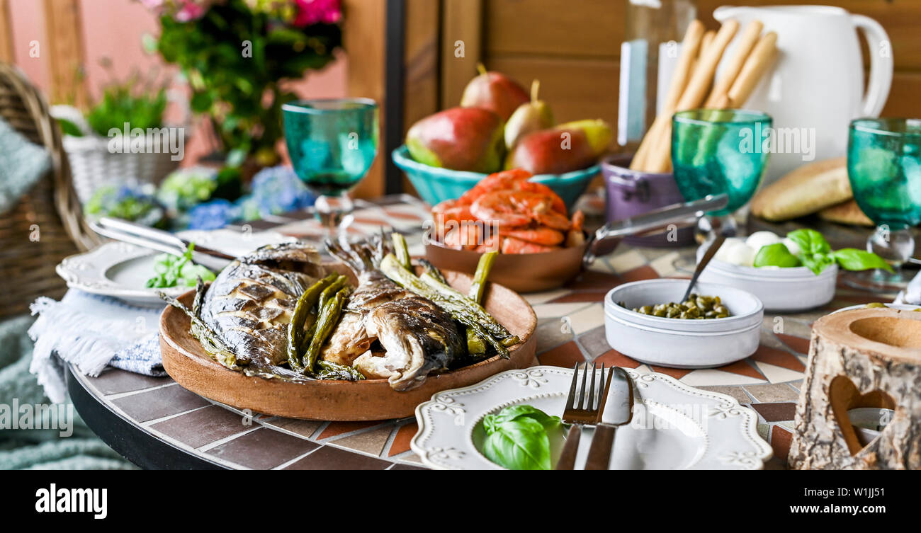 Fried fish on a plate. Dining table with different food and snacks ...