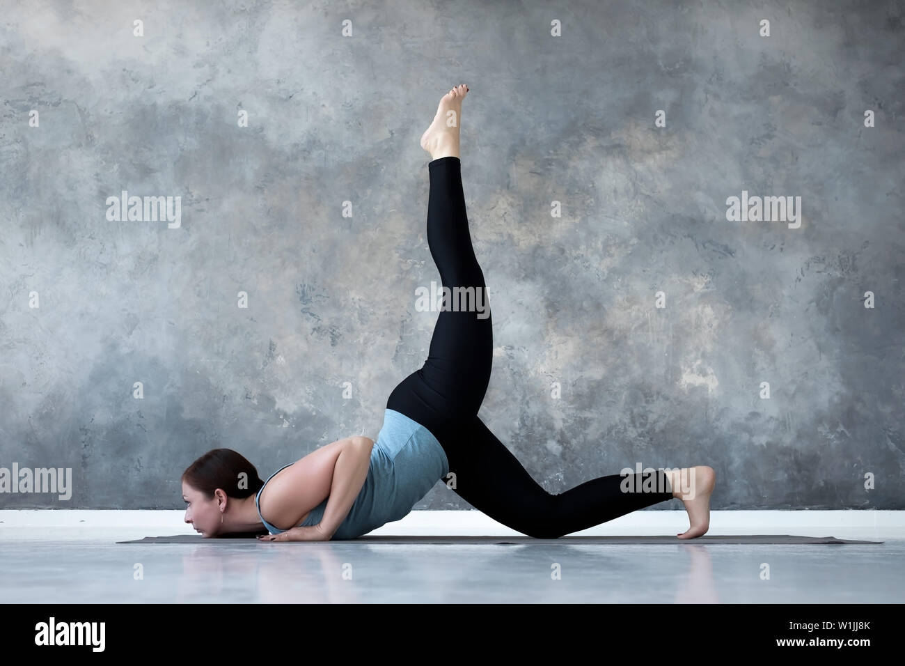 Woman practicing yoga doing eka pada Shalabhasana, the Locust pose ...