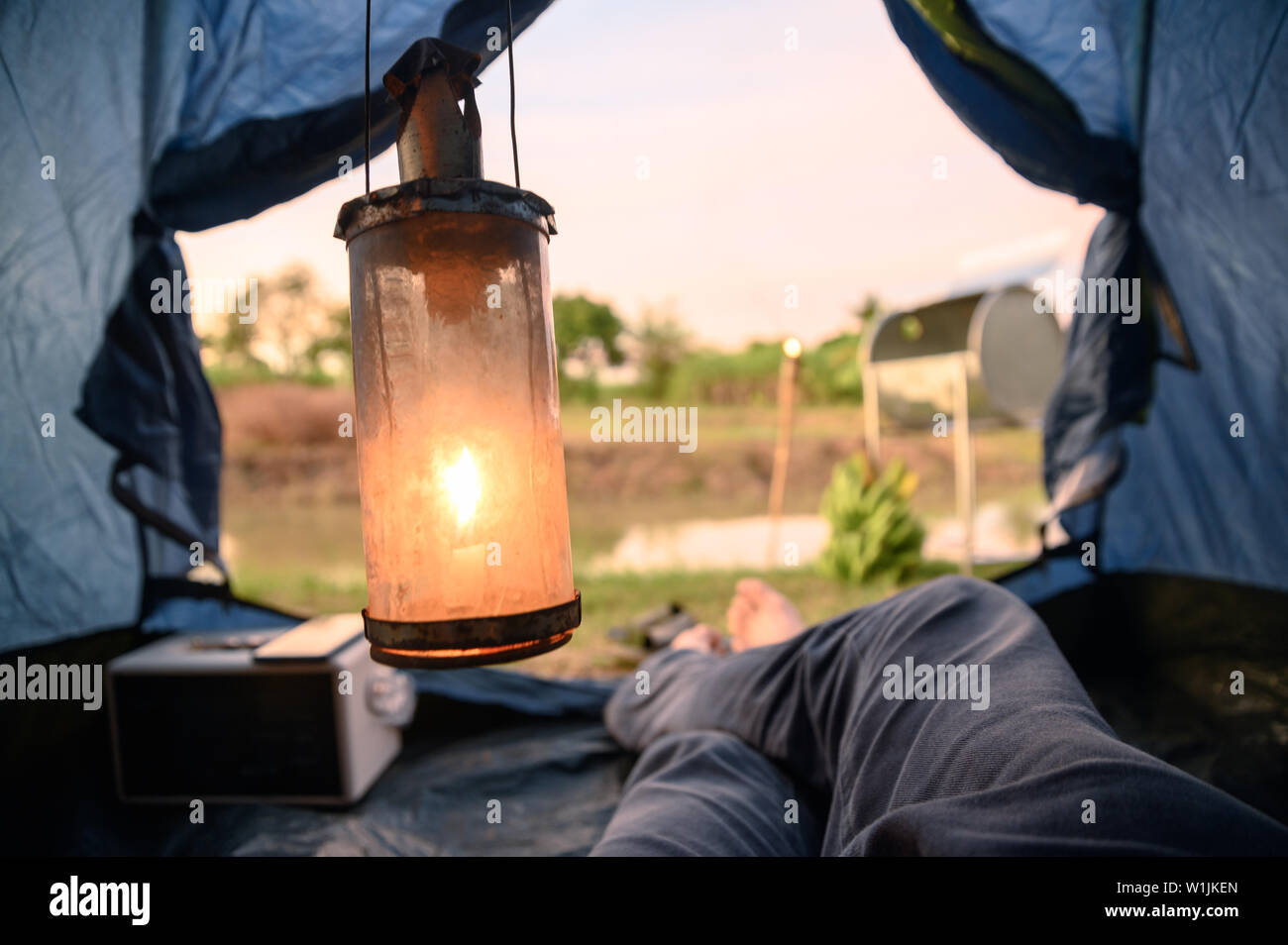 View from inside of tent with lantern shine and campfire near swamp ...