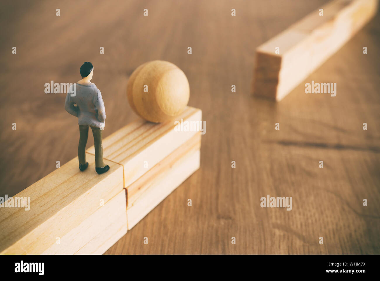 Concept image of business and challenge. A man has to roll a ball over ...