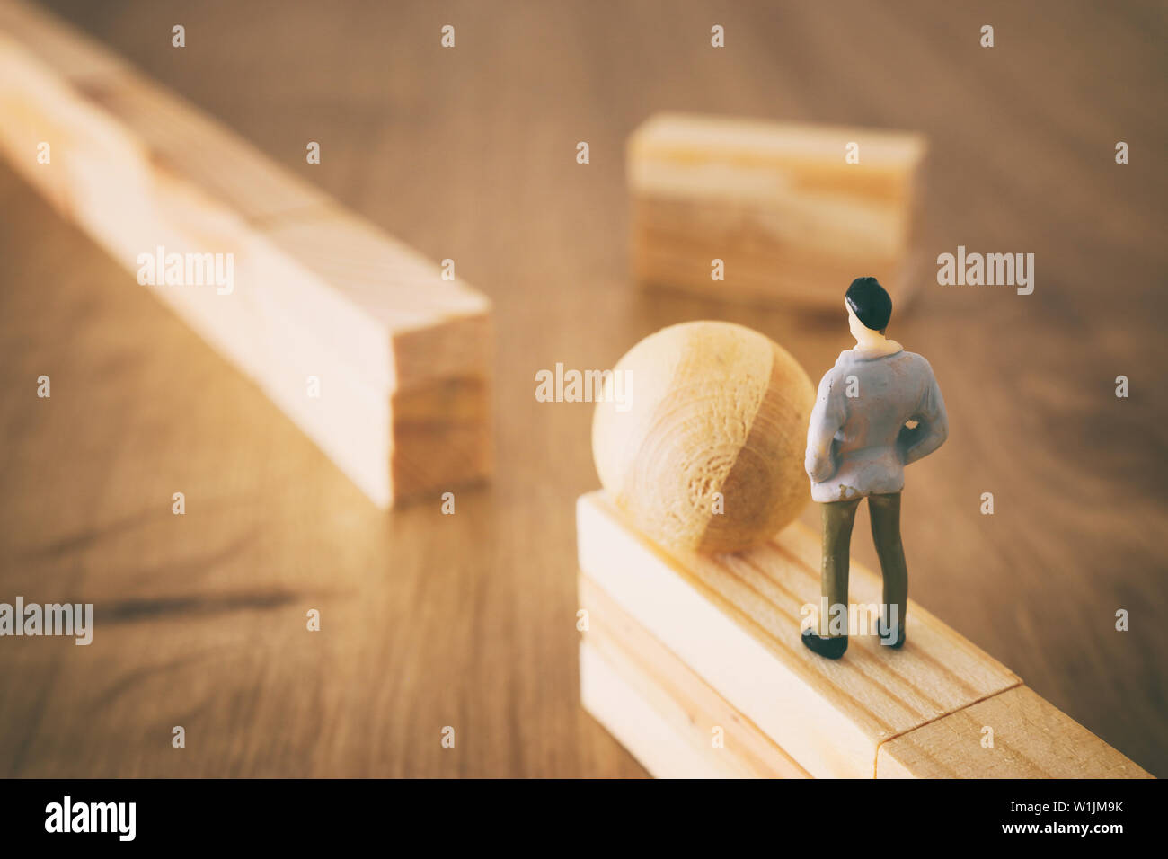 Concept image of business and challenge. A man has to roll a ball over ...