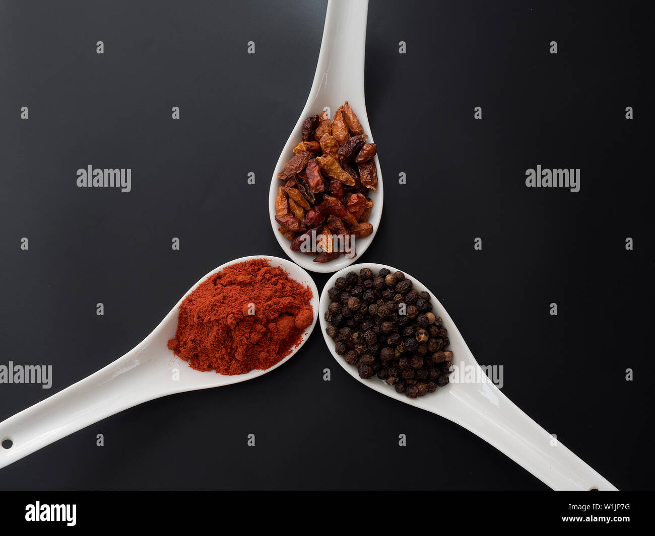 Spicy spices in white spoons on black background Stock Photo - Alamy