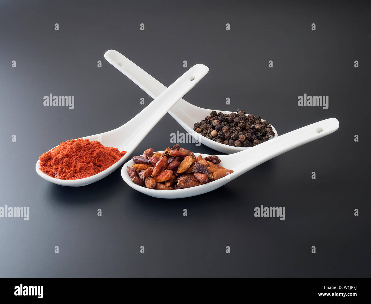 Spicy spices in white spoons on black background Stock Photo - Alamy