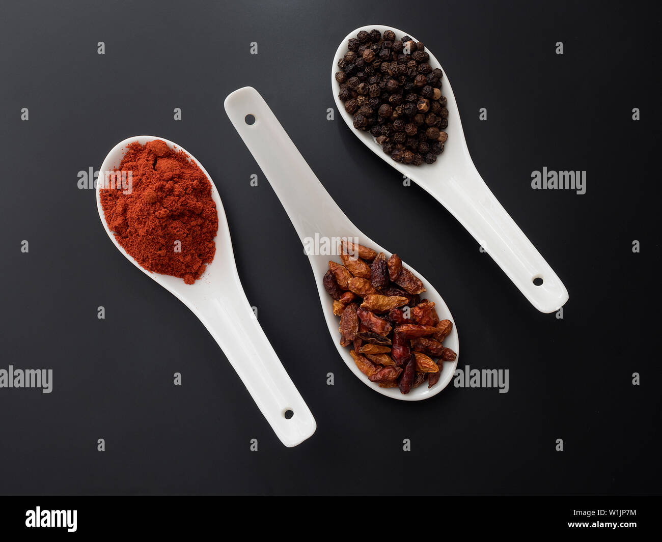 Spicy spices in white spoons on black background Stock Photo - Alamy