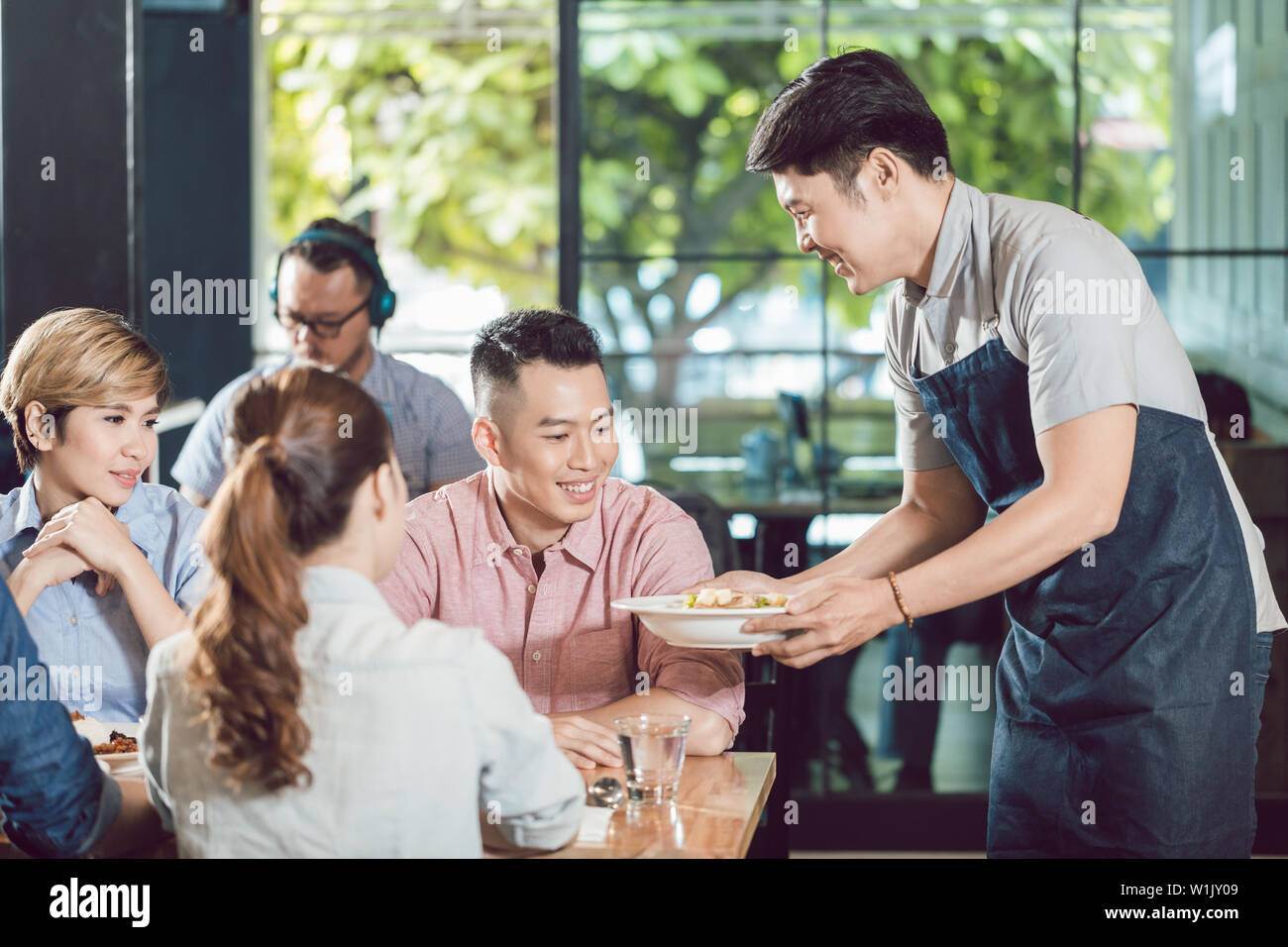 Smiling male waiter serving food in the restaurant Stock Photo - Alamy