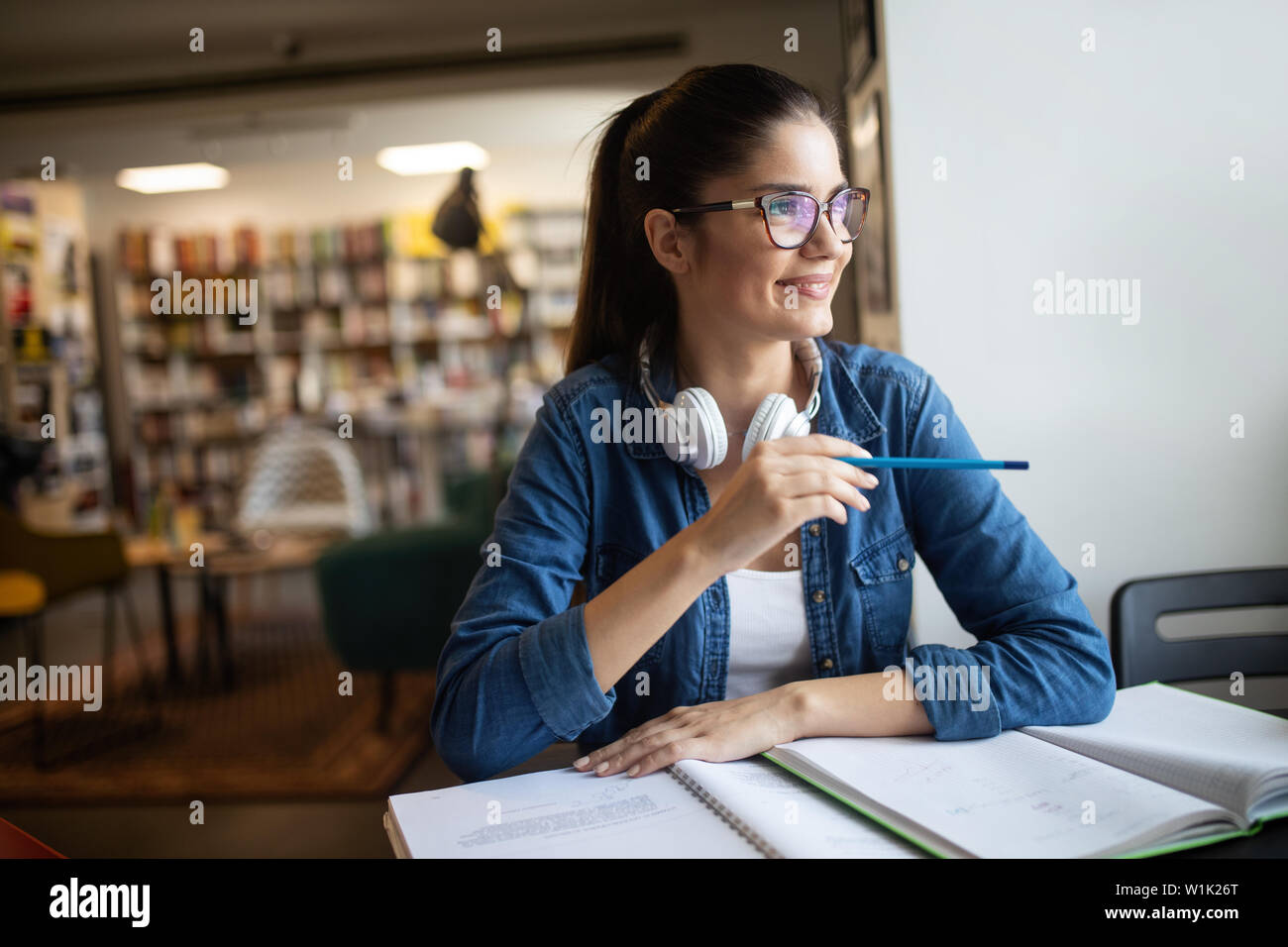 Beautiful student girl learning in a library Stock Photo - Alamy