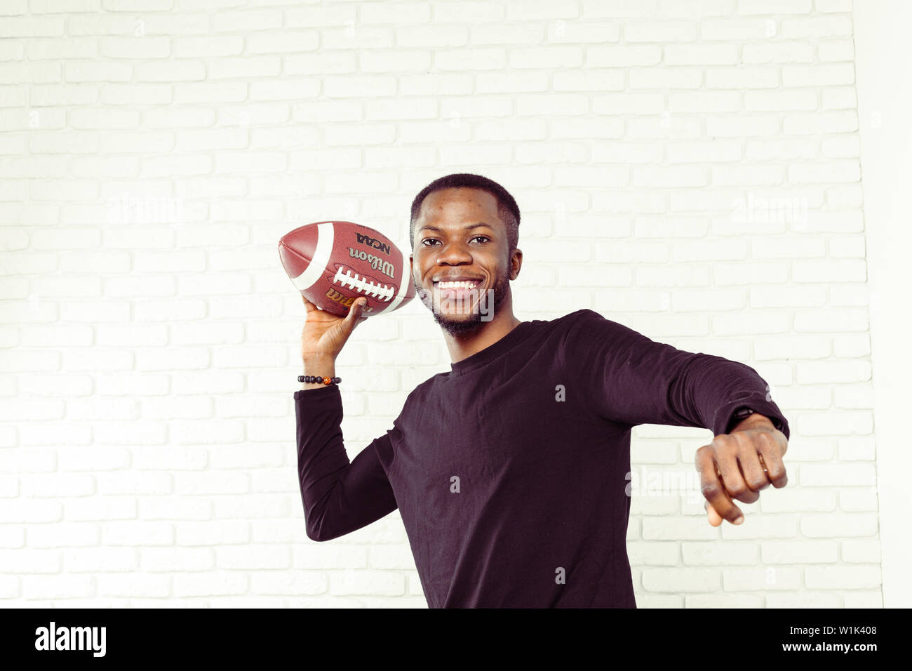 Friendly smiling black man holding a football Stock Photo - Alamy
