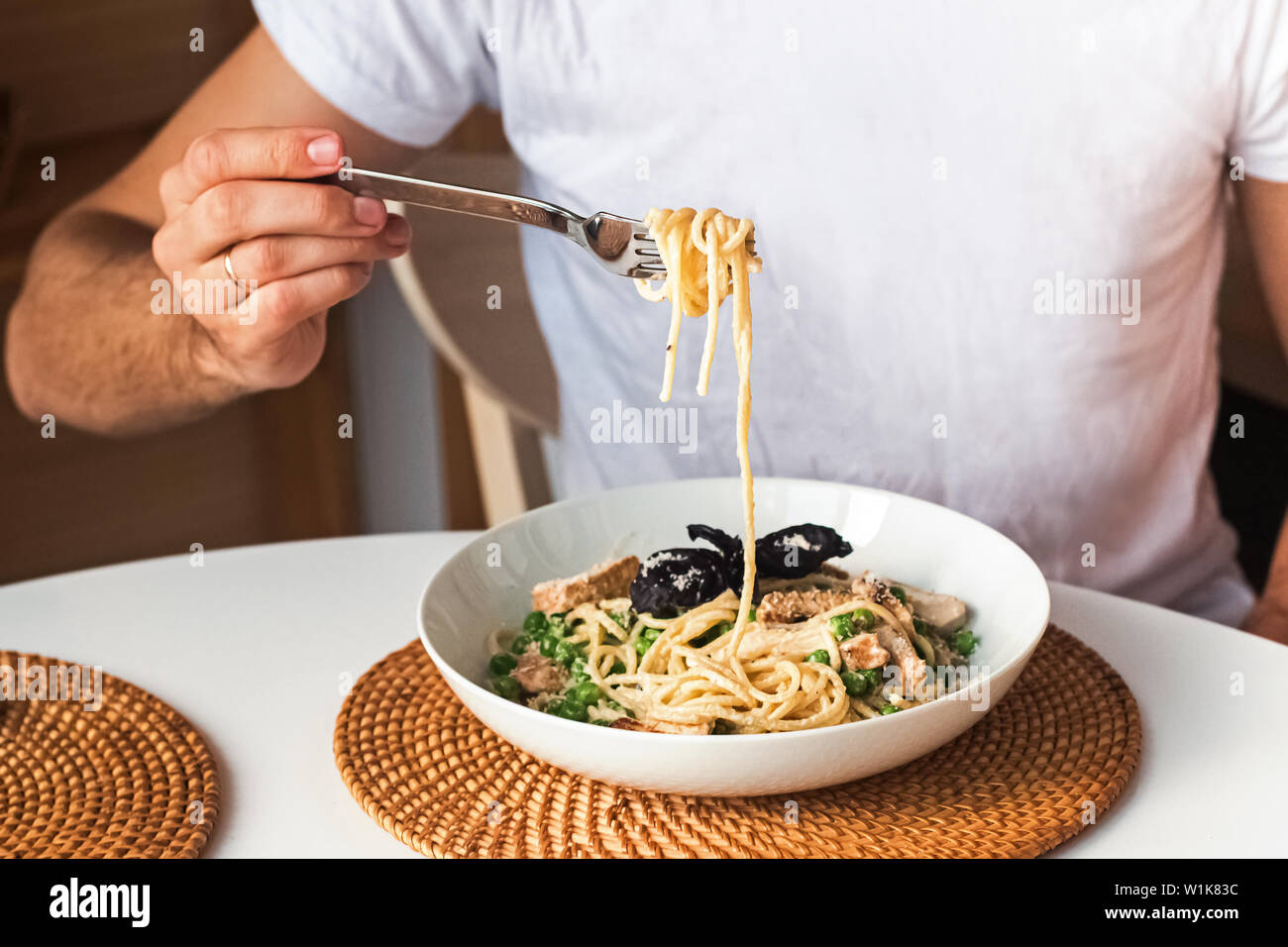 Man eating delicious pasta with peas close-up Stock Photo - Alamy