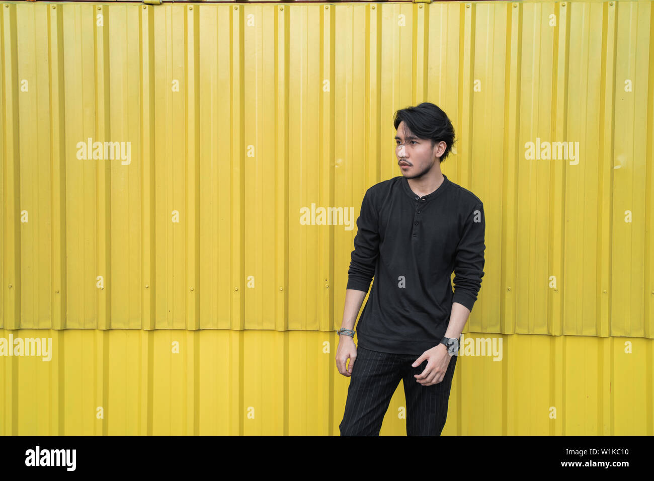 Young man standing front yellow background Stock Photo - Alamy