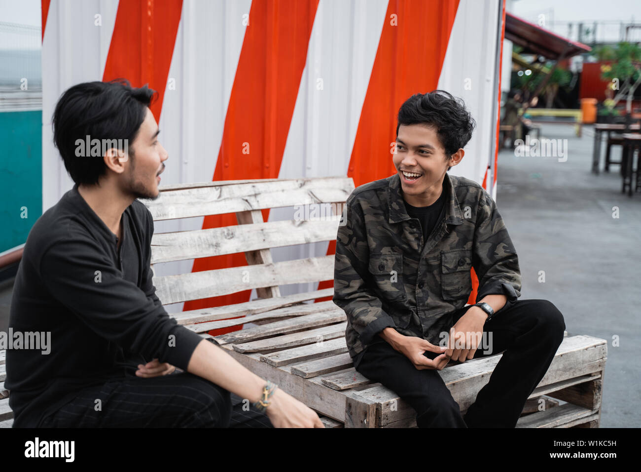two friends chatting sitting on the wooden chair Stock Photo - Alamy
