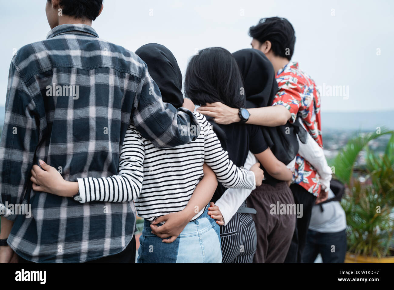 Rear view of young friends sitting together on rooftop Stock Photo - Alamy