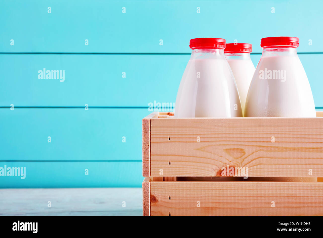Traditional milk bottles in a wooden crate on wooden kitchen table with ...