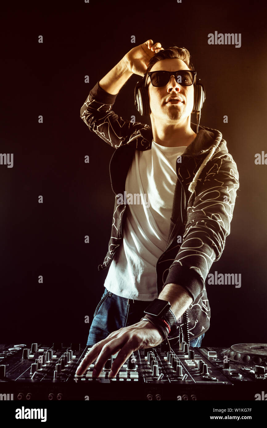 DJ mixing music on mixer on dark background Stock Photo - Alamy