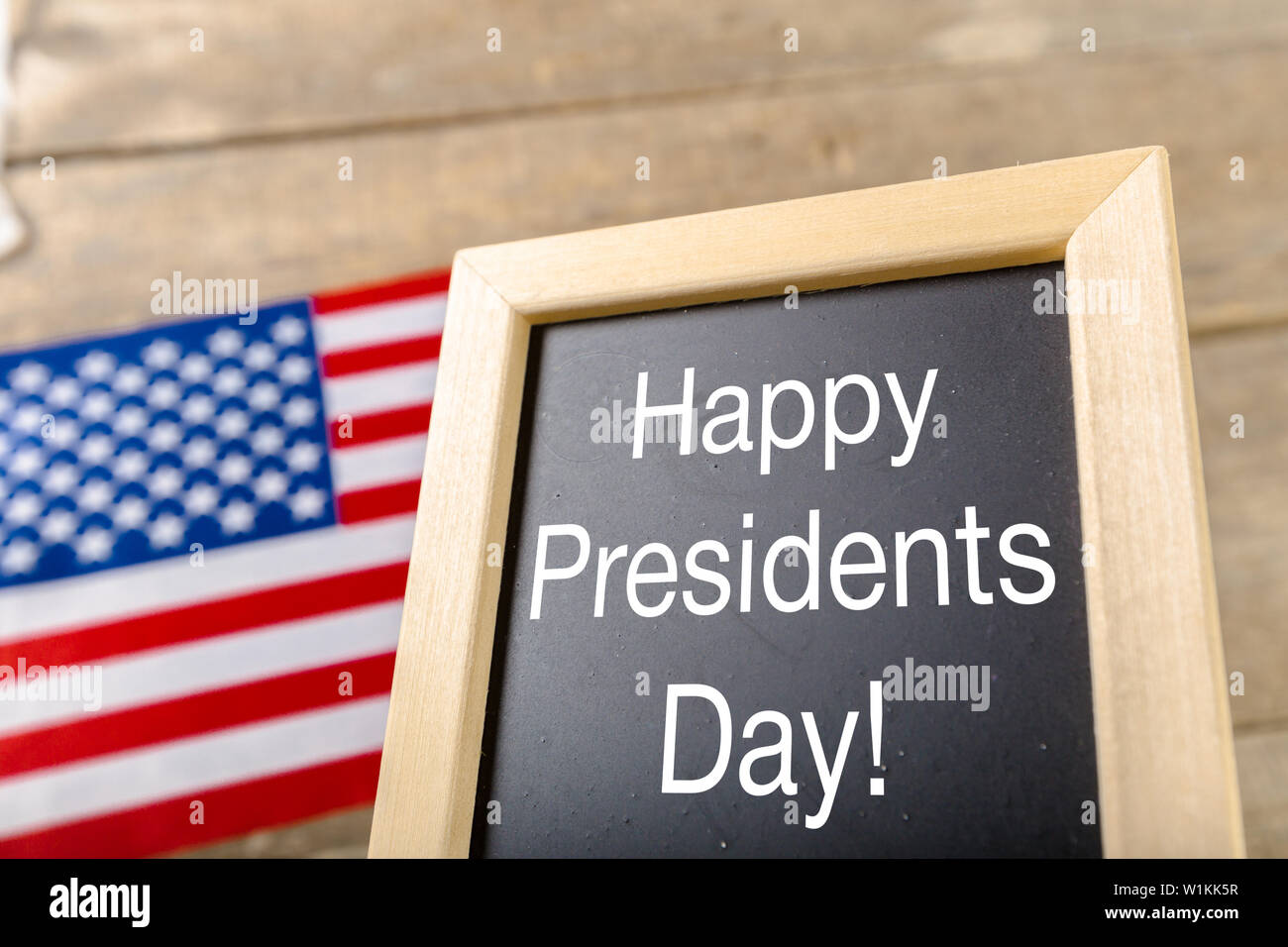 the text happy presidents day written in a chalkboard and a flag of the ...
