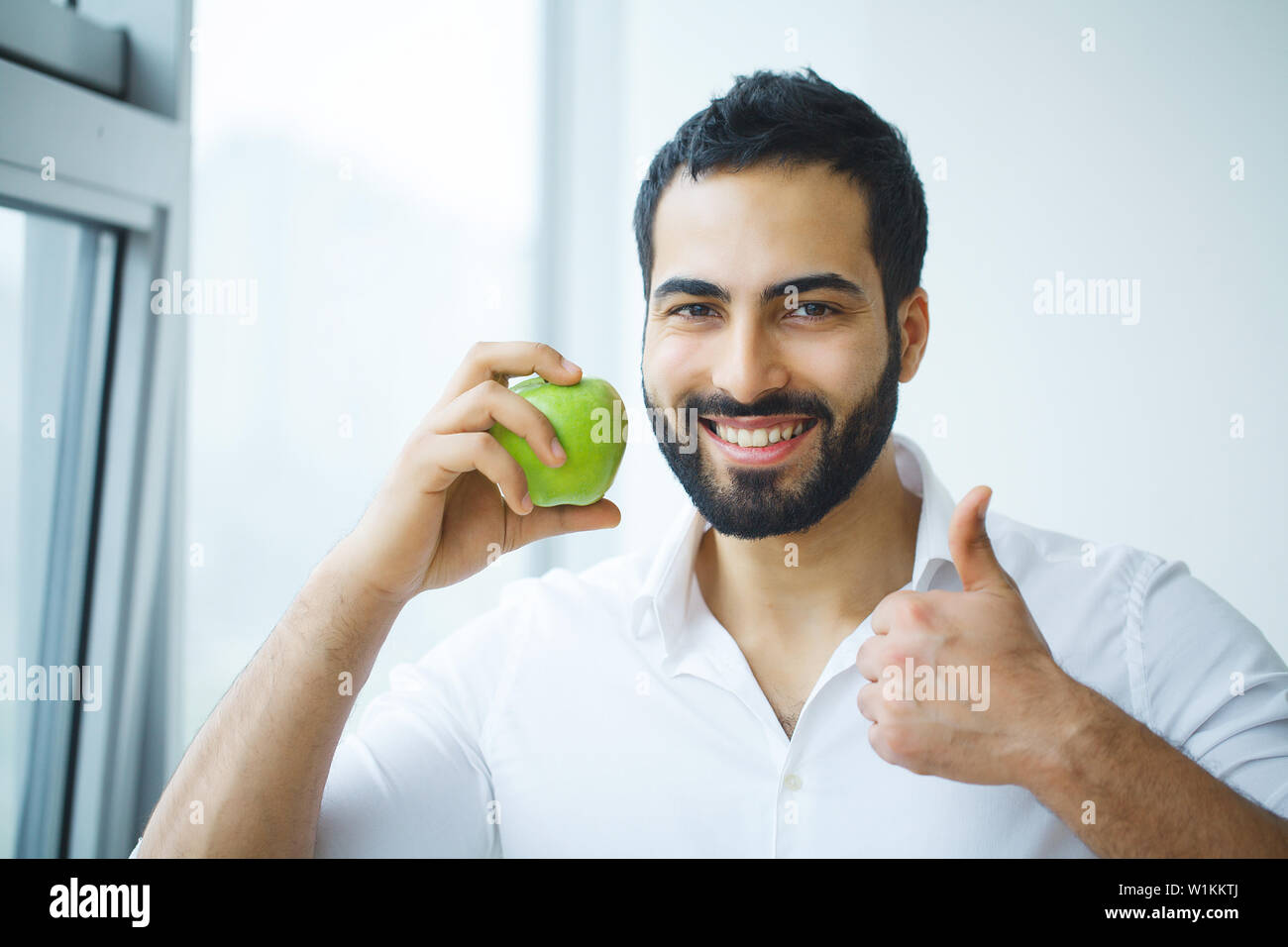 Man With Apple. Beautiful male With White Smile, Healthy Teeth. High ...