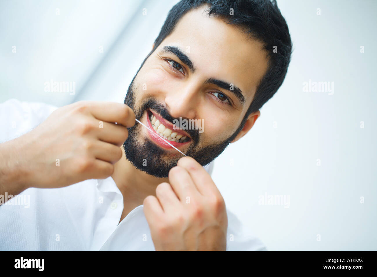 Teeth Care. Beautiful Smiling Man Flossing Healthy White Teeth. High ...
