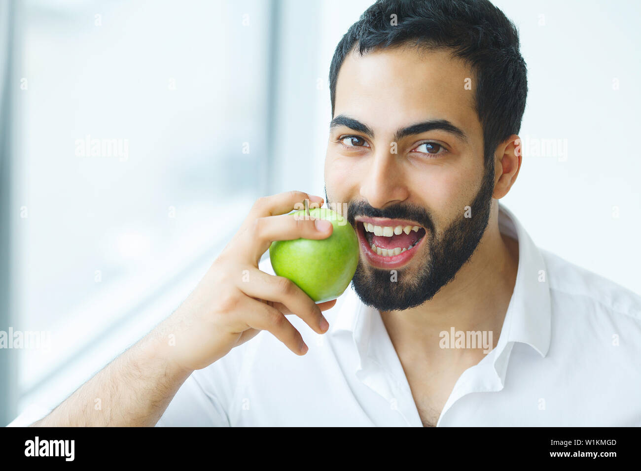 Man With Apple. Beautiful male With White Smile, Healthy Teeth. High ...