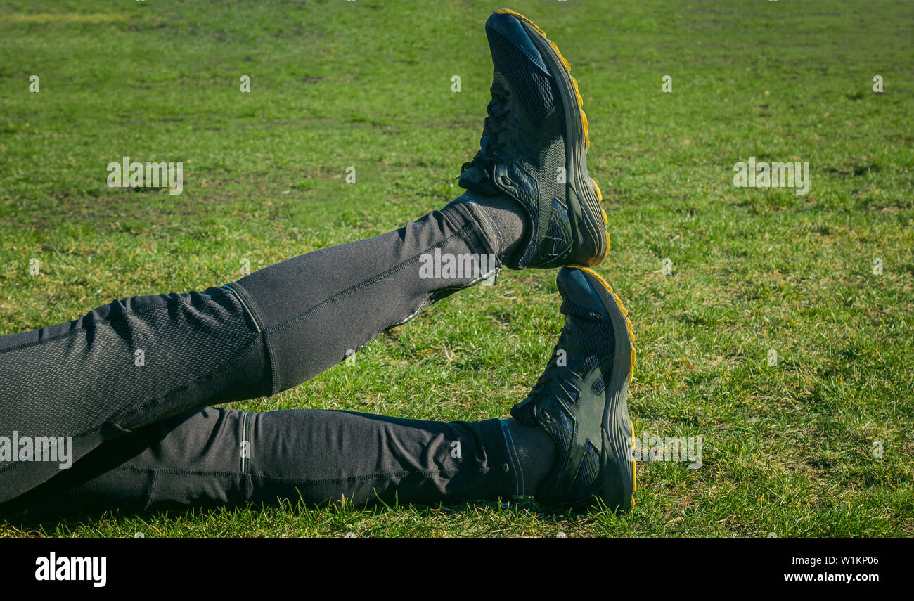 athlete's legs in leggings and sneakers, lying on the ground on the ...