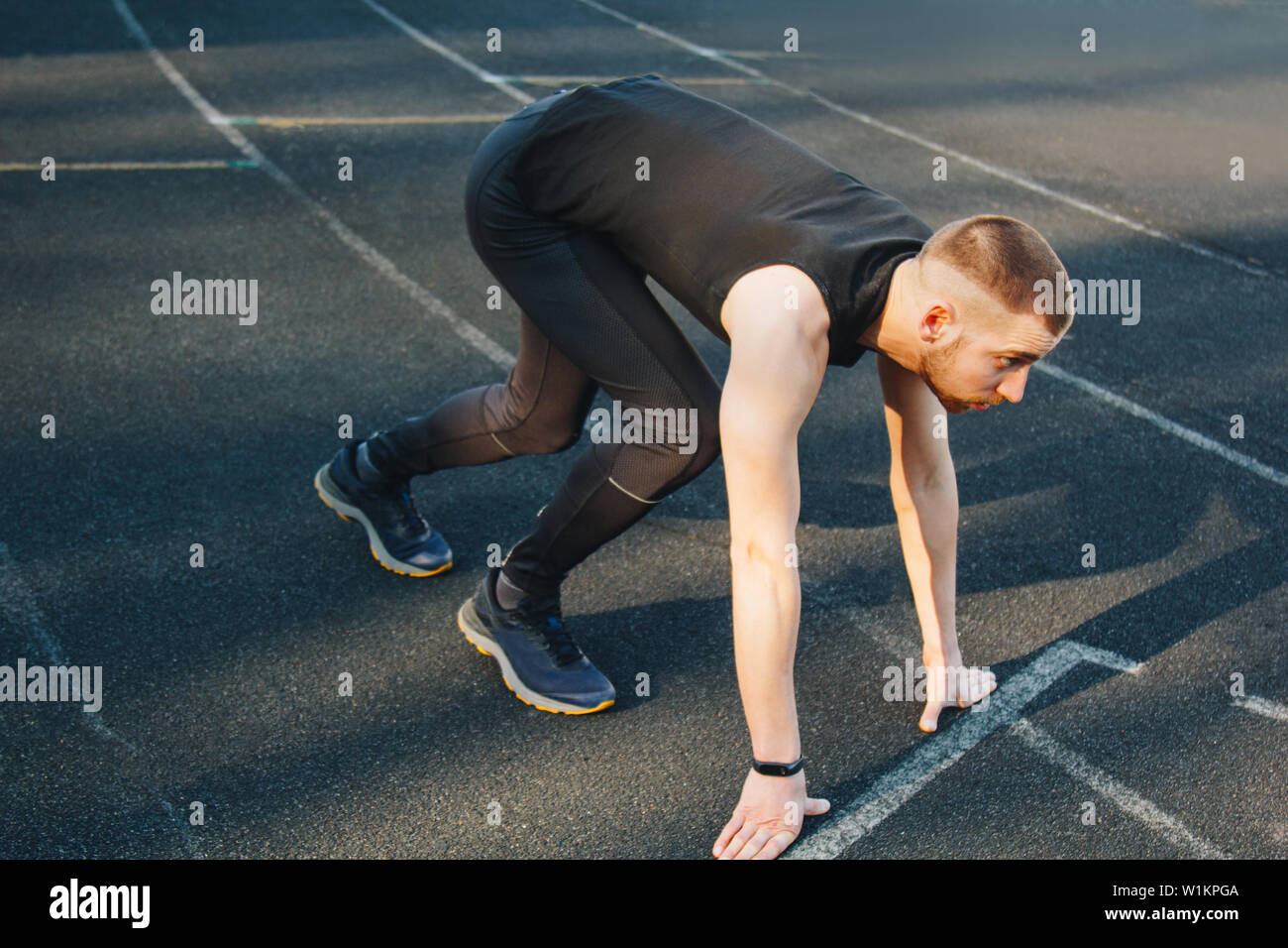 one man on the start line awaits the start of the sprint. stadium ...