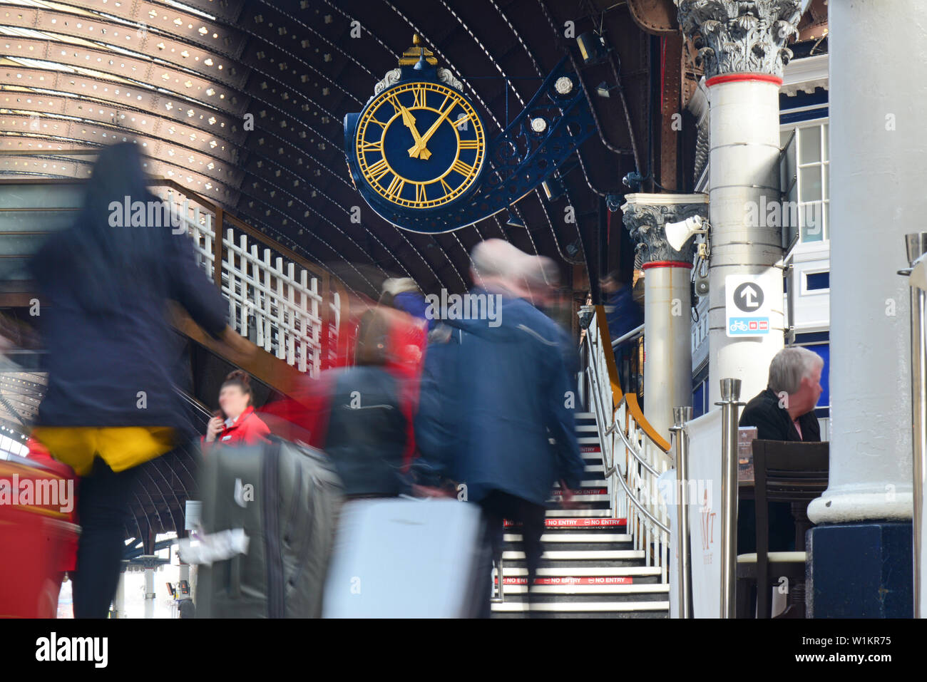 passengers passing station clock rushing to catch trains at york ...
