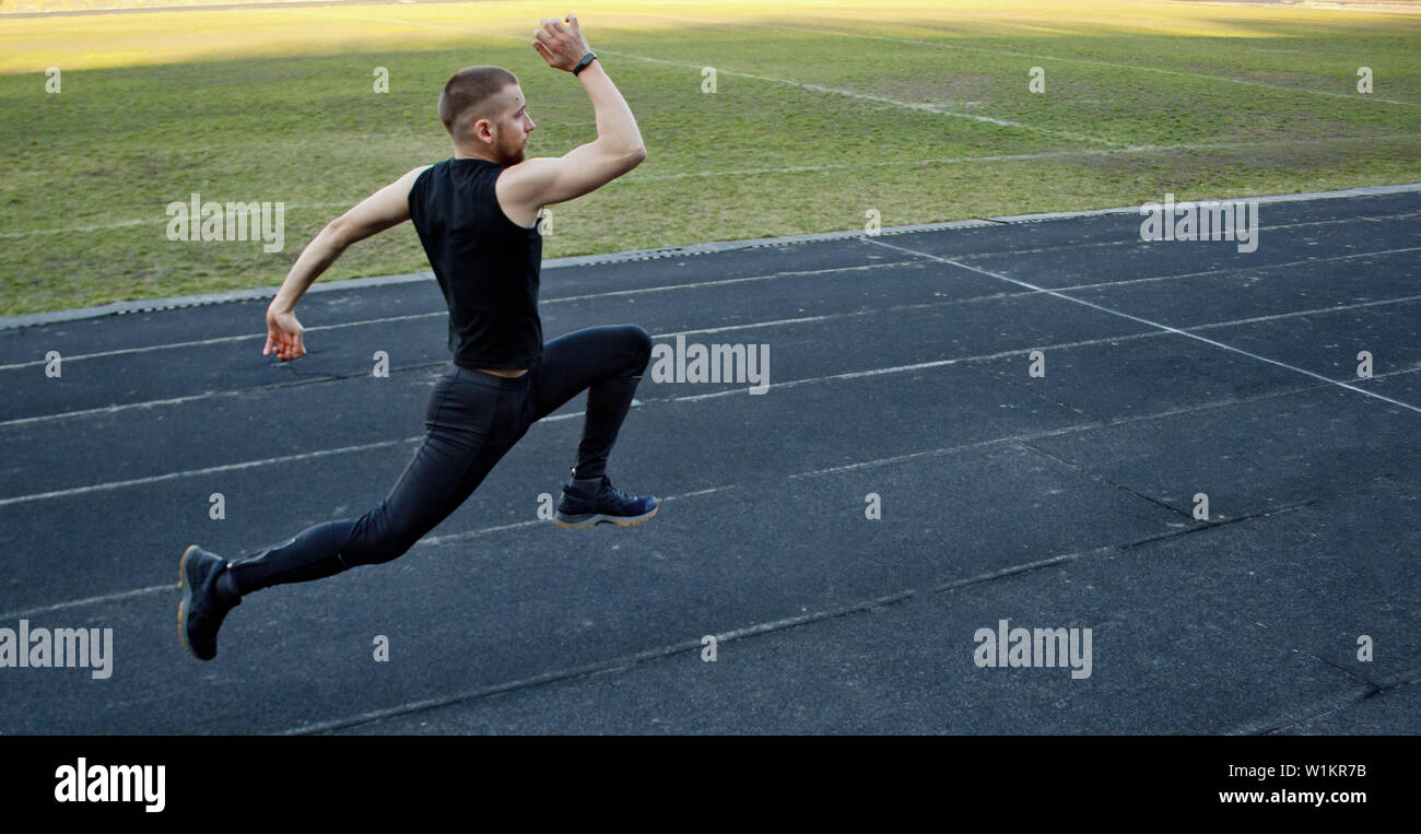 one caucasian male is doing a sprint start. running on the rubber track ...