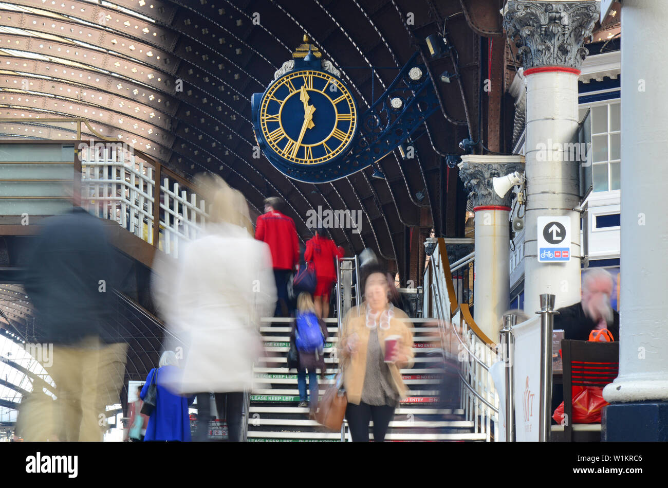 passengers passing station clock rushing to catch trains at york ...