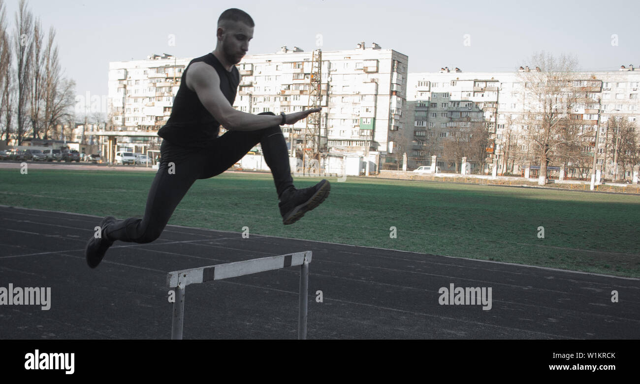 one caucasian male in a jump over a barrier. running on the stadium ...