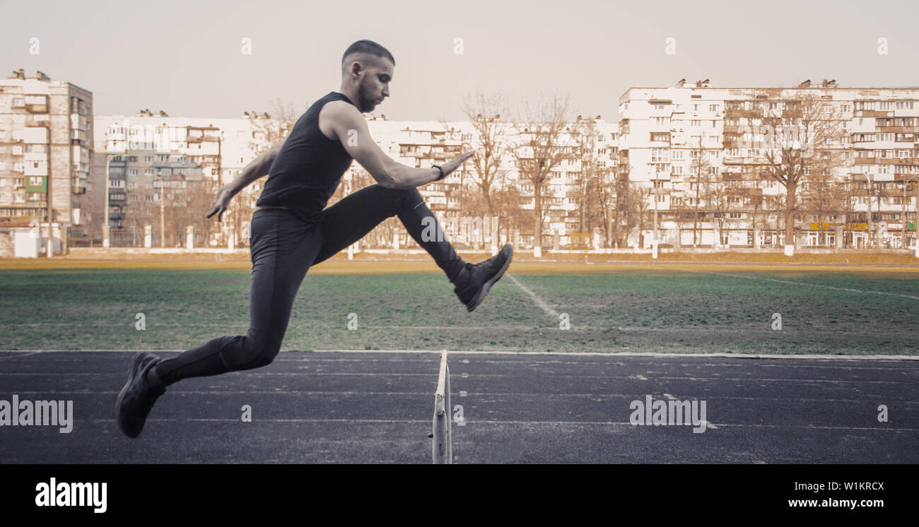 one caucasian male in a jump over a barrier. running on the stadium ...