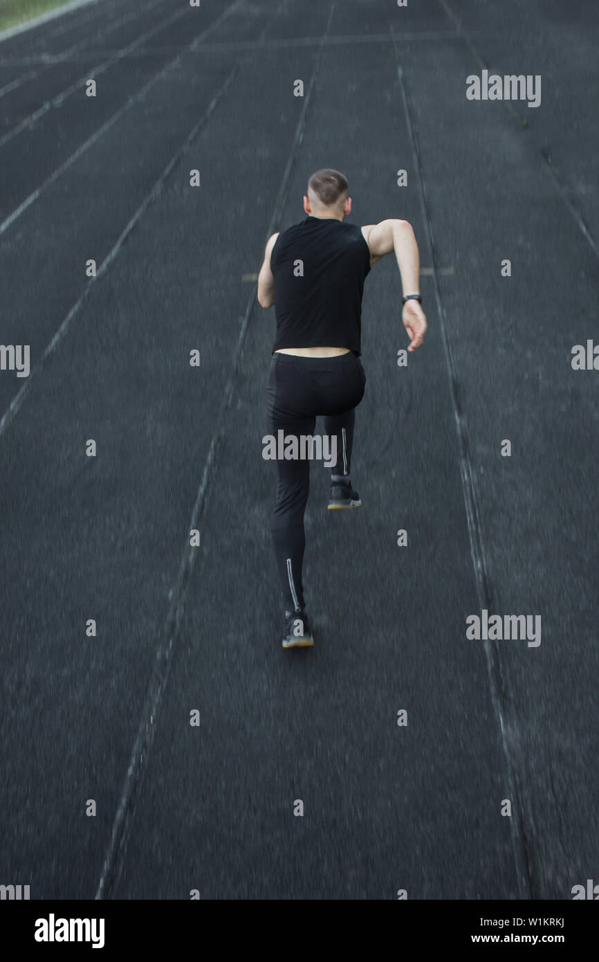 caucasian man doing a sprint start. running on the stadium on a track ...