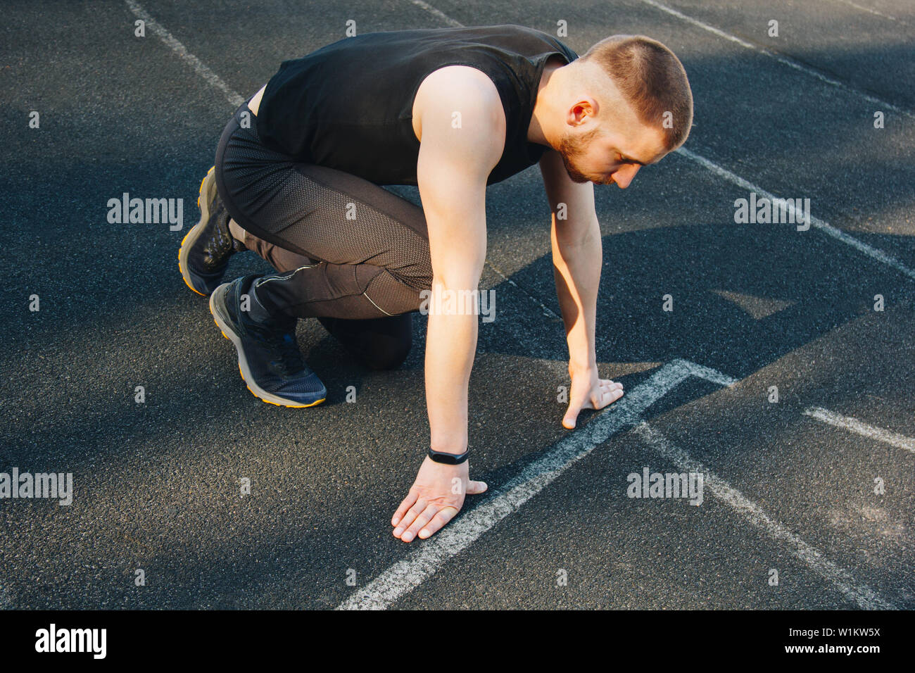 one man on the start line awaits the start of the sprint. stadium ...