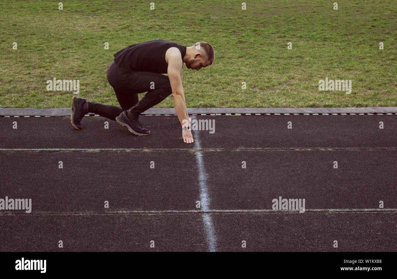 one man on the start line awaits the start of the sprint. stadium ...