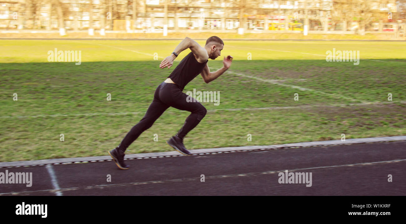 one caucasian male is doing a sprint start. running on the stadium on a ...