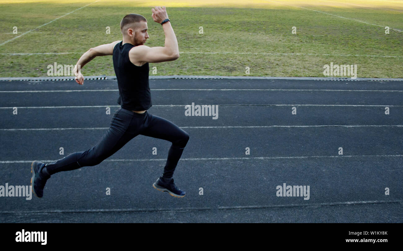 one caucasian male is doing a sprint start. running on the rubber track ...