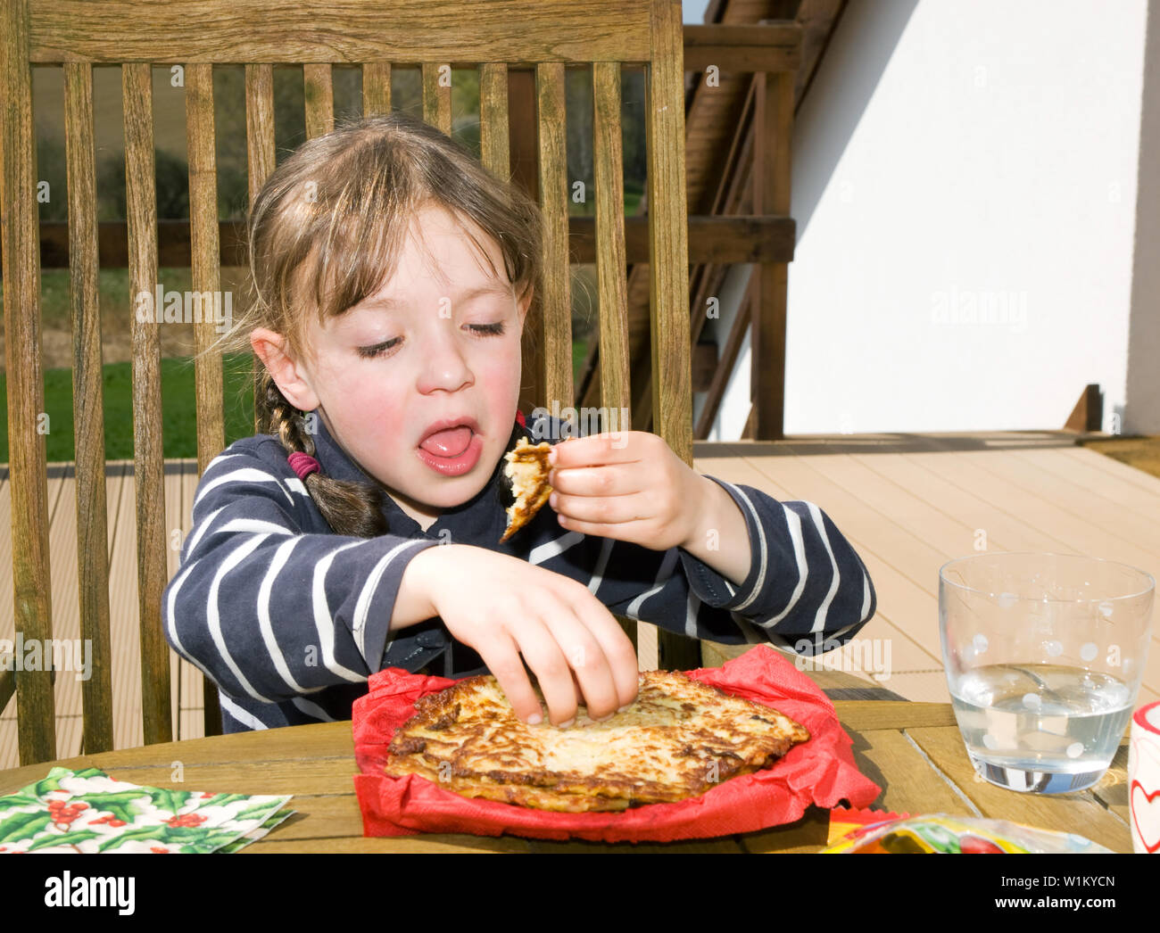 Little girl eating potato pancake Stock Photo - Alamy