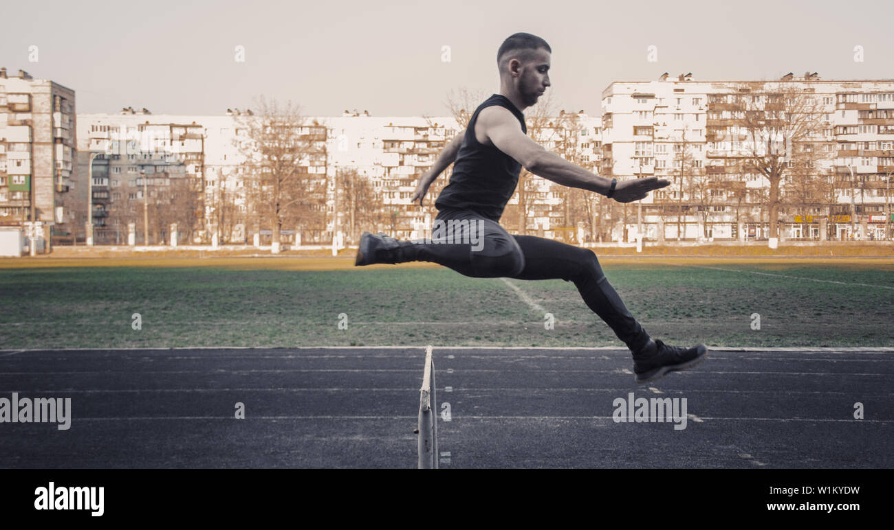 one caucasian male in a jump over a barrier. running on the stadium ...