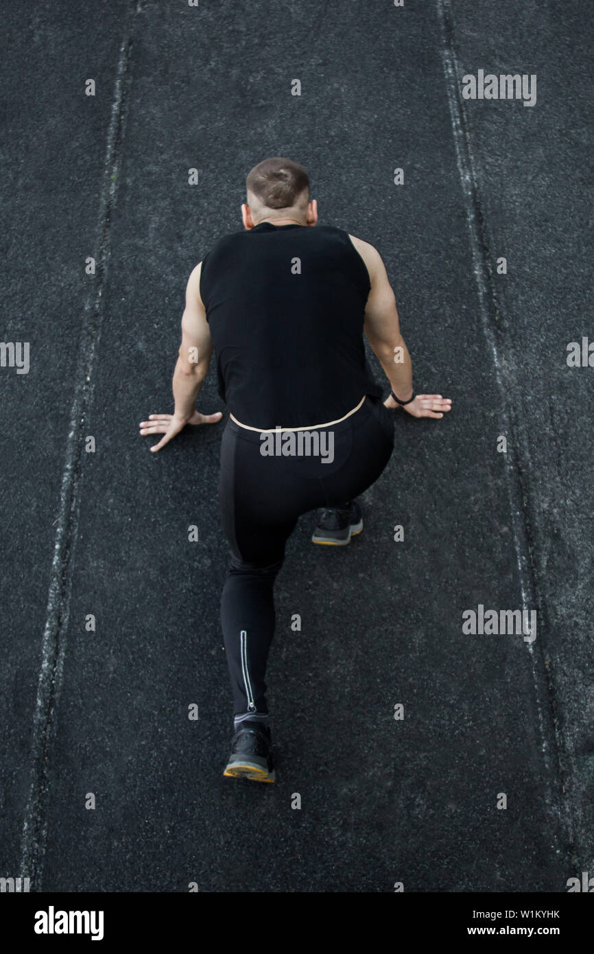 caucasian man doing a sprint start. running on the stadium on a track ...
