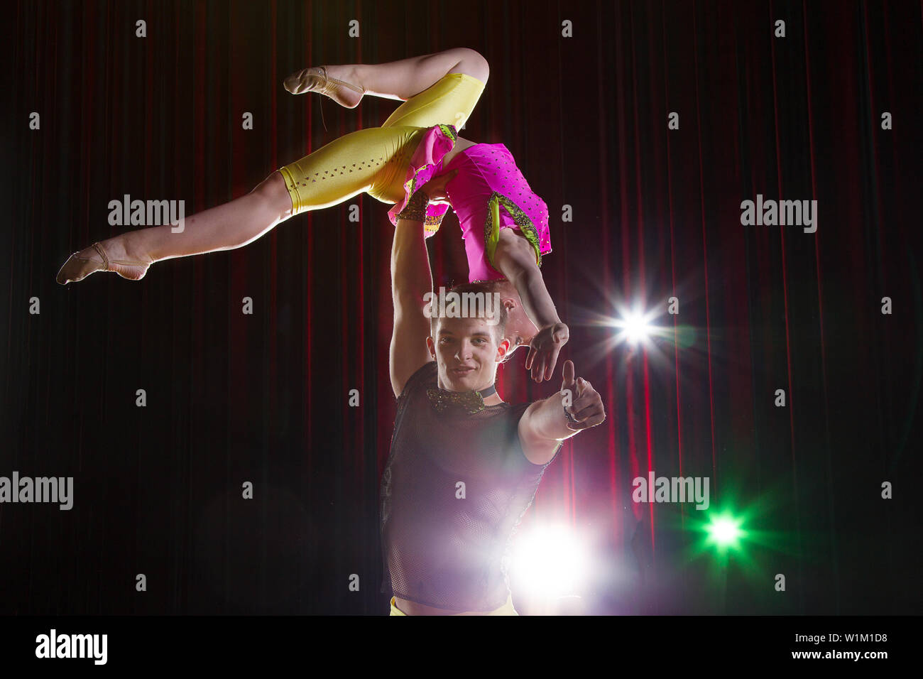 Circus artists perform acrobatics. The gymnast guy holds a girl on his ...