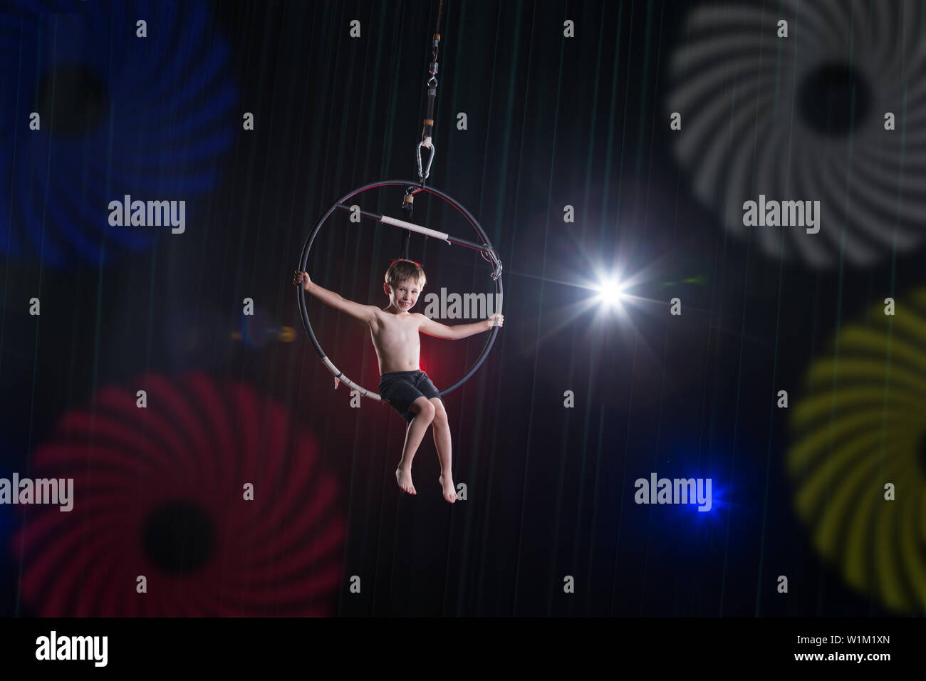 Performs a circus little boy artist. Circus aerial gymnast on the hoop ...