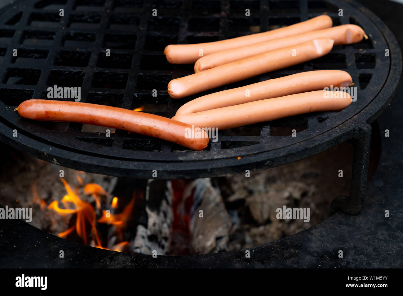 description: Grilled sausages on grill with smoke and flame on dark ...