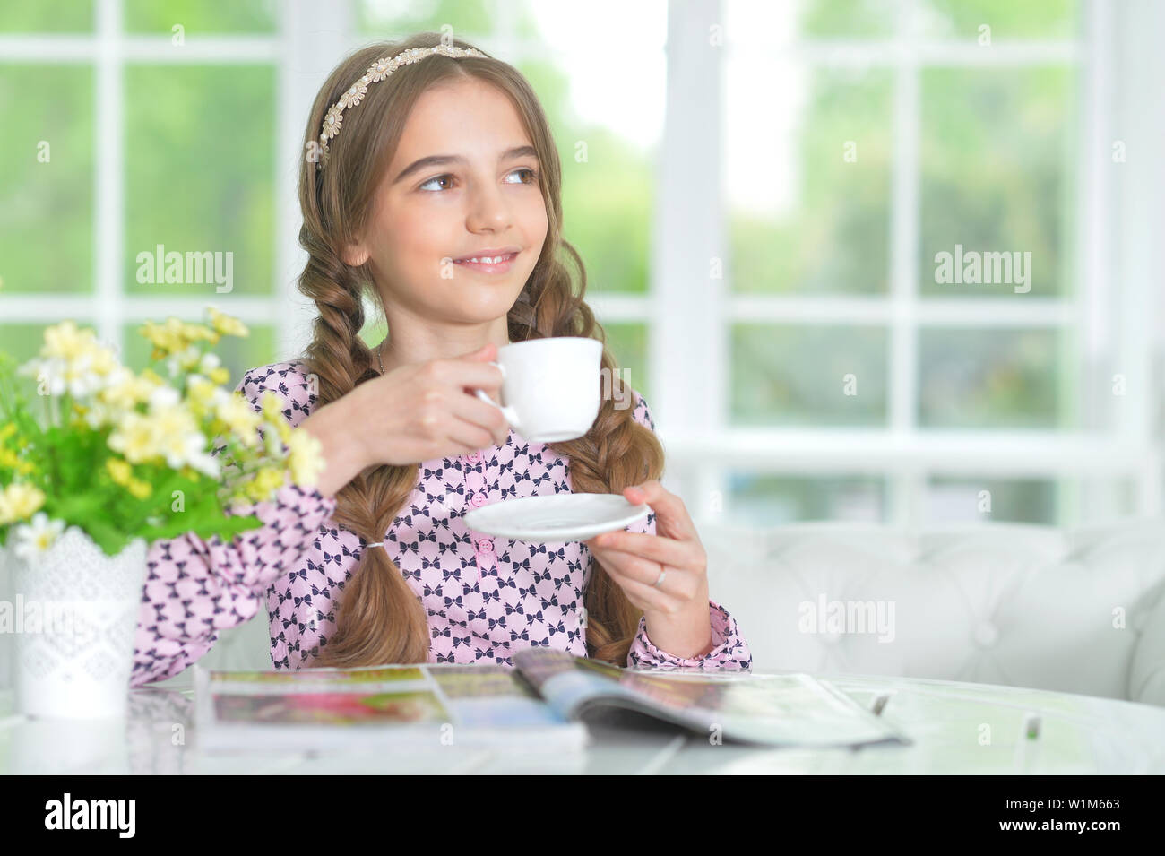 Portrait of cute girl drinking tea while reading magazine Stock Photo ...