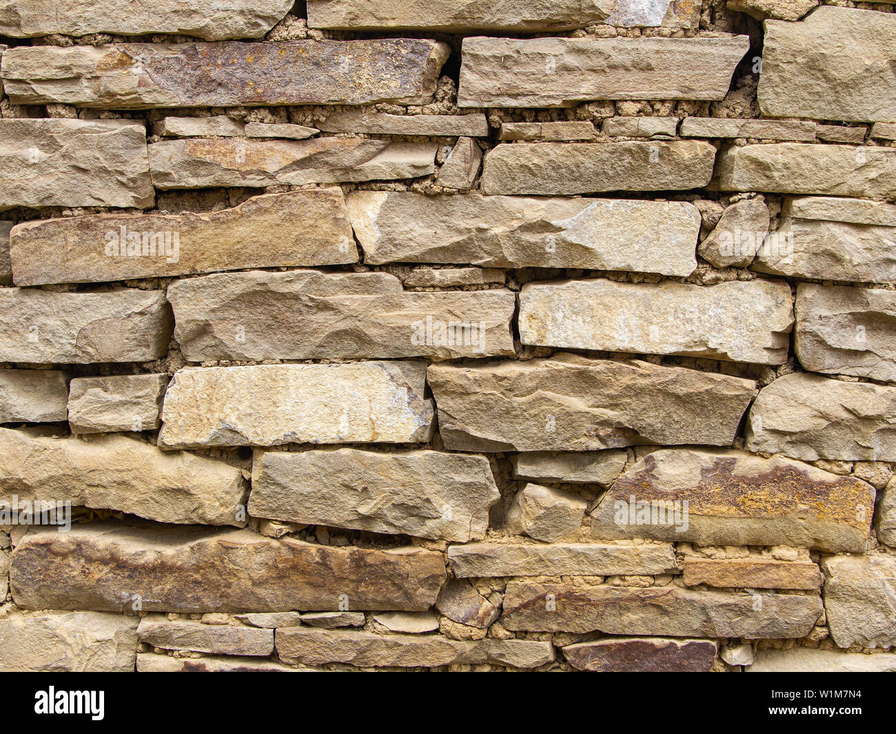 Fragment of masonry made of yellow and brown stone under natural light ...