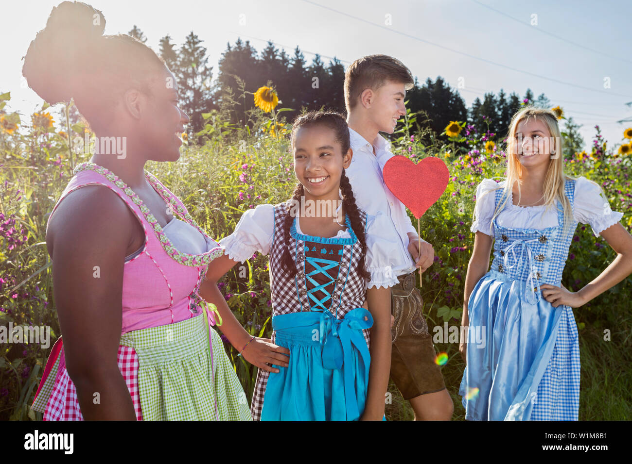 Happy teenage friends in front of sunflower field, Bavaria, Germany ...